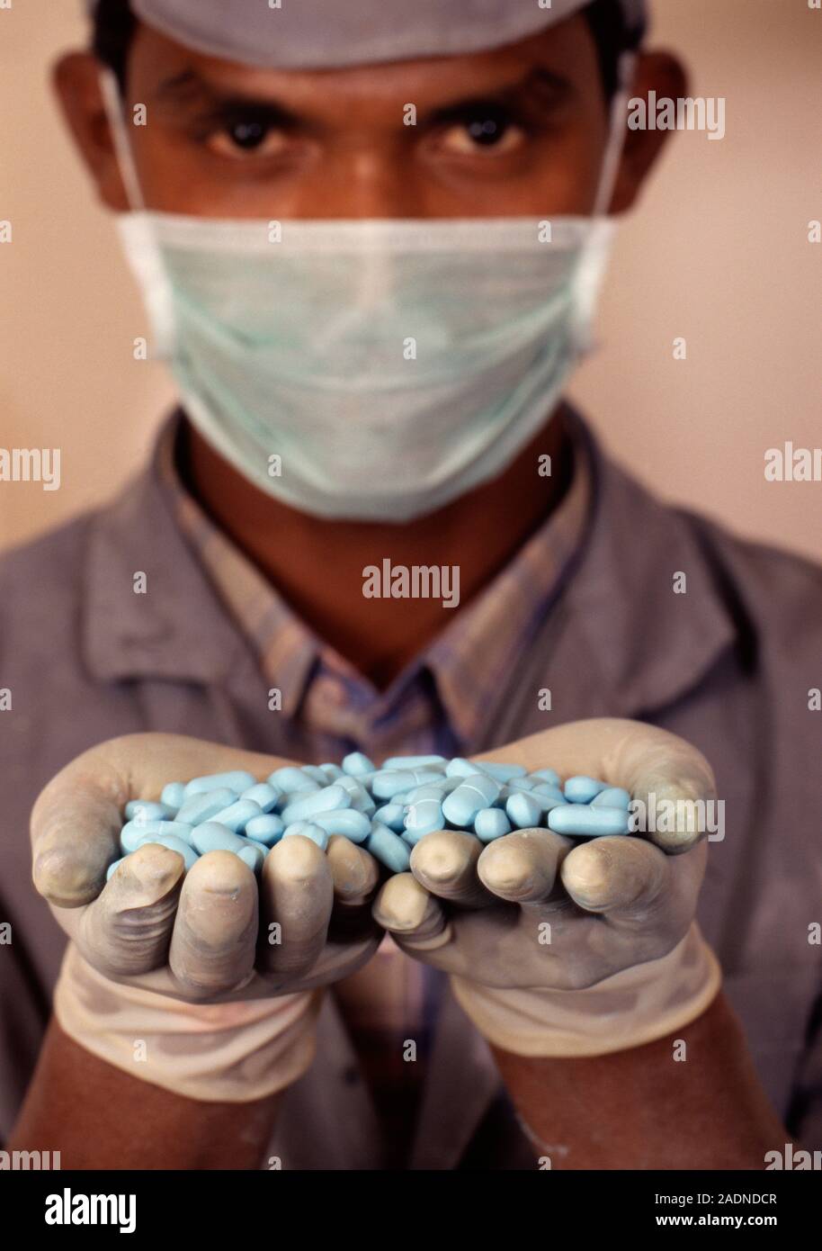 Drug manufacture. Worker holding a handful of pills at a factory in ...