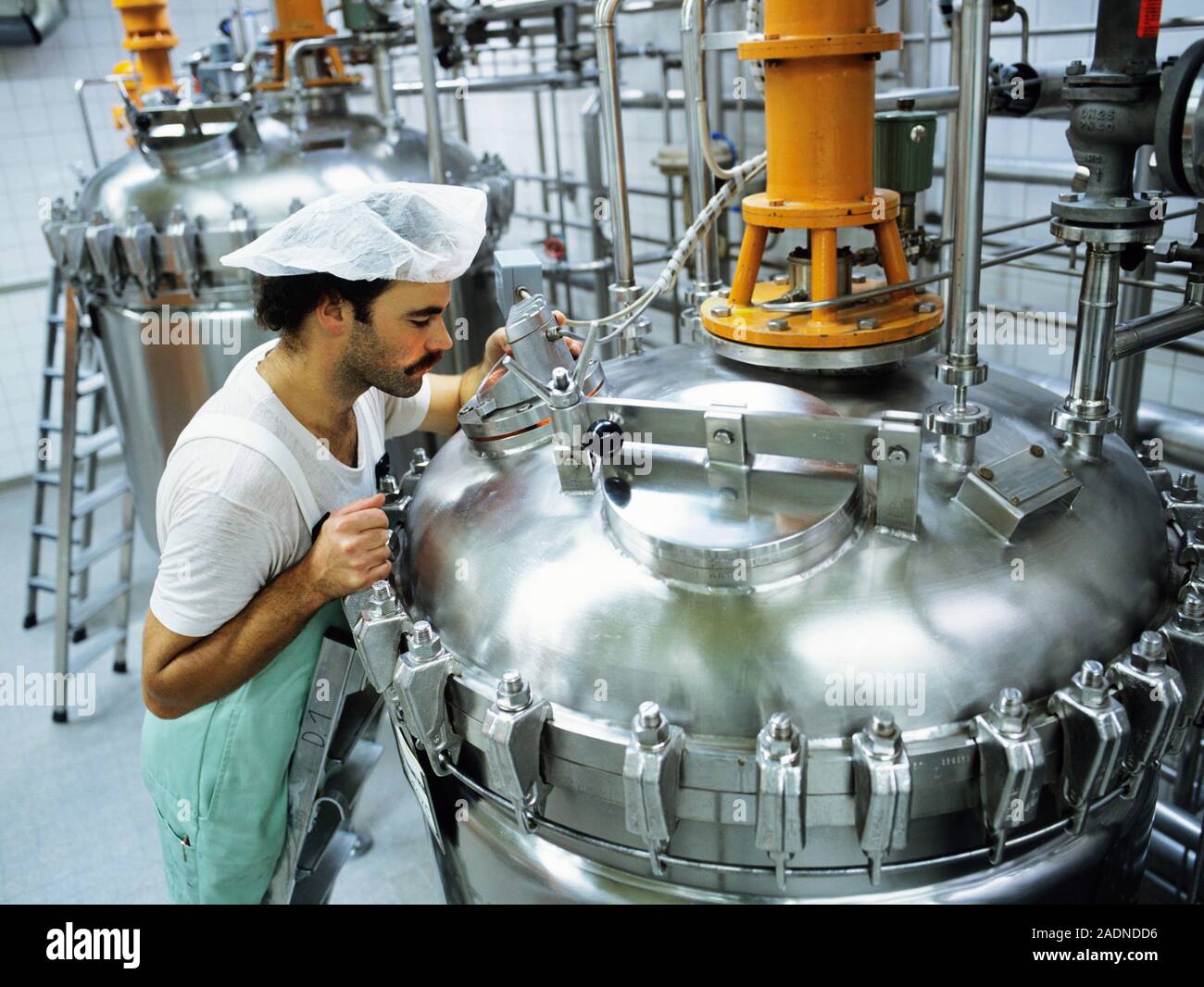 Drug manufacture. Technician inspecting pills in a vat at a ...