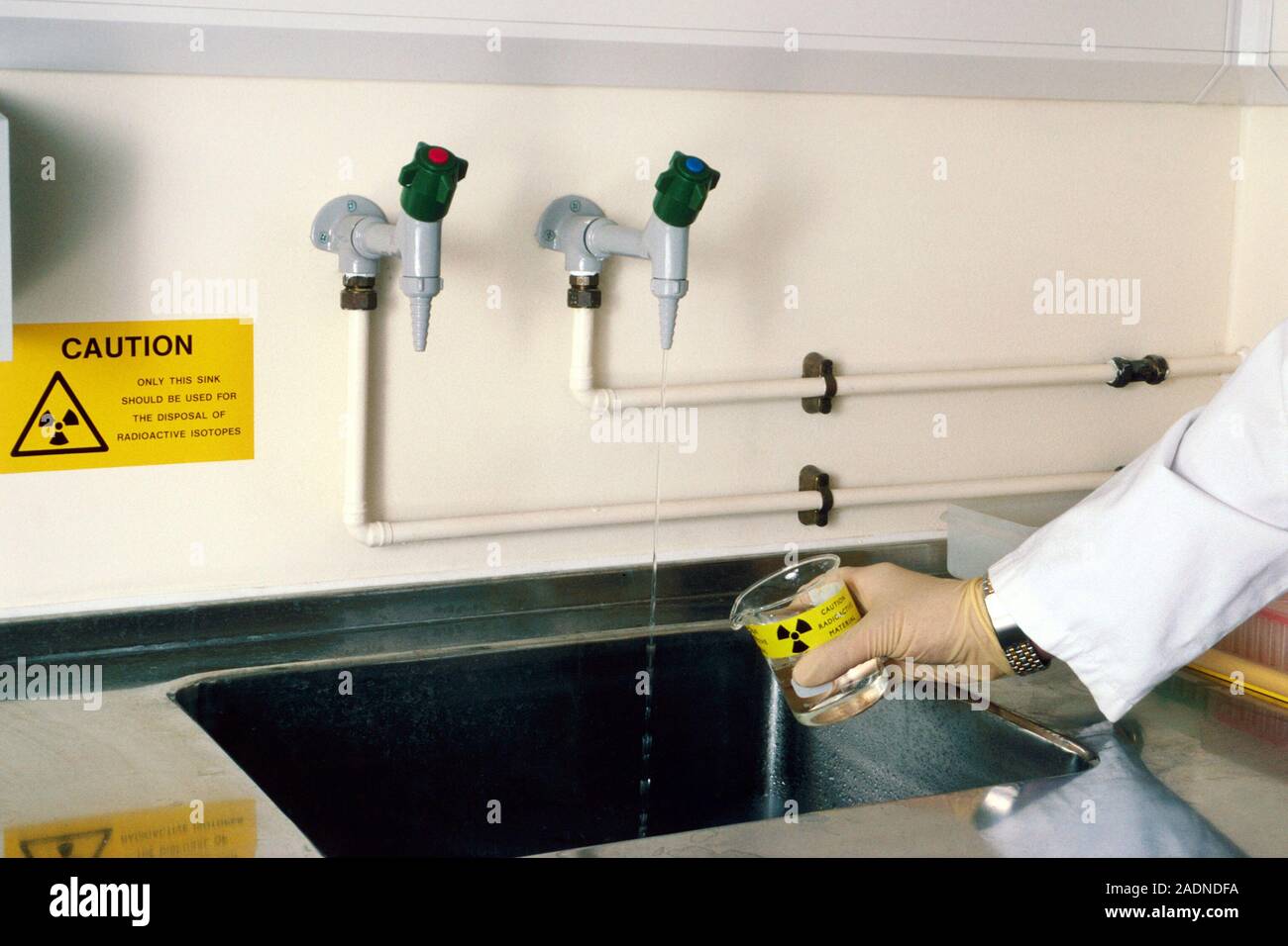 MODEL RELEASED. Radioactive laboratory work. Chemist pouring ...