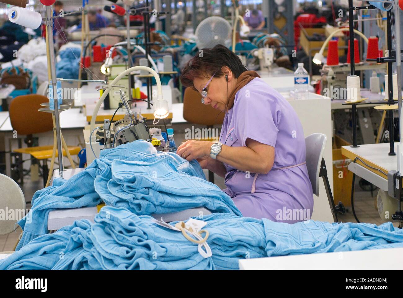 Textile industry. Worker using a sewing machine to assemble the final ...