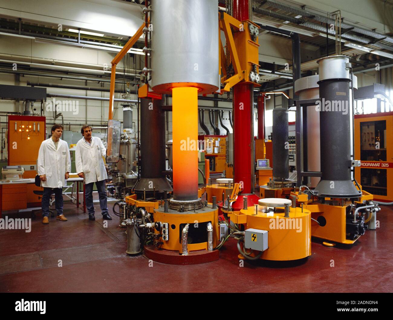 Sintering furnace. Factory workers using a shield to safely view a ...