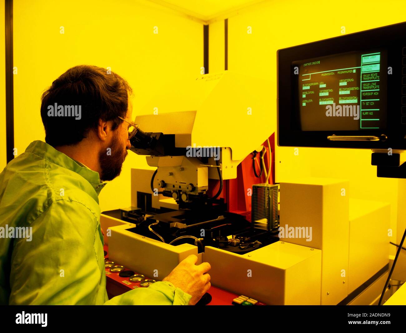Thin film manufacture. Technician using a microscope to visually ...