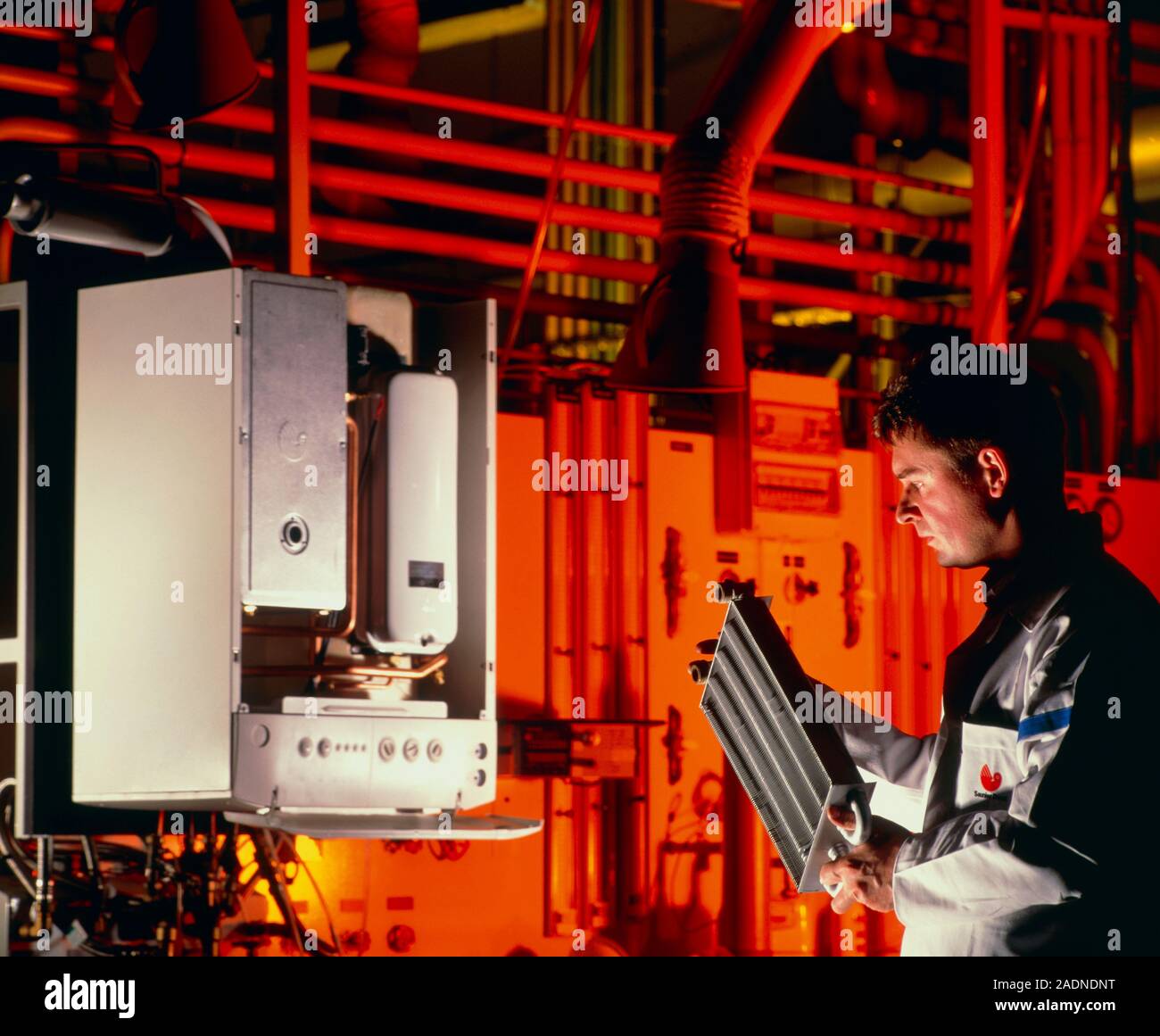 Boiler test. Worker testing a water boiler (white) after manufacture as ...