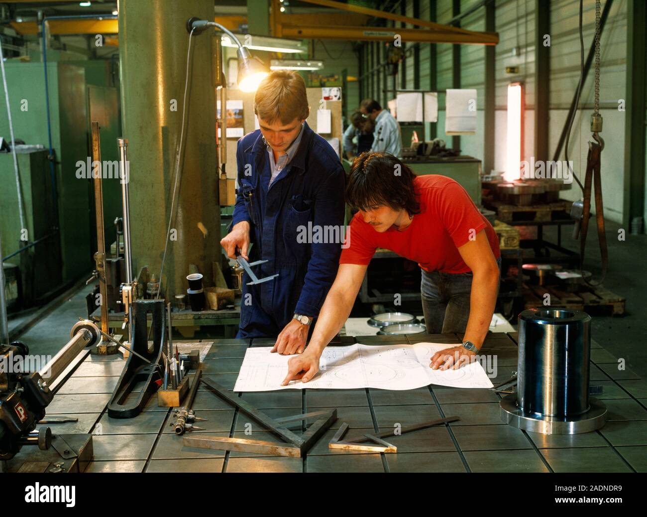 Toolmaking. Mechanical engineer (right) marking out points for ...
