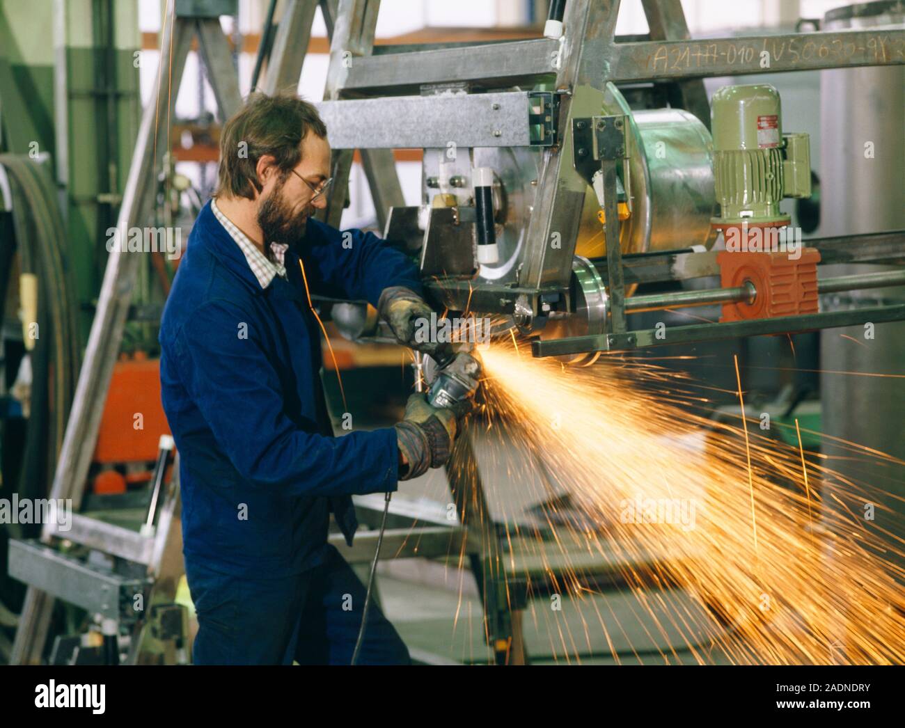 Assembling an industrial furnace. Worker using a cutting tool while ...