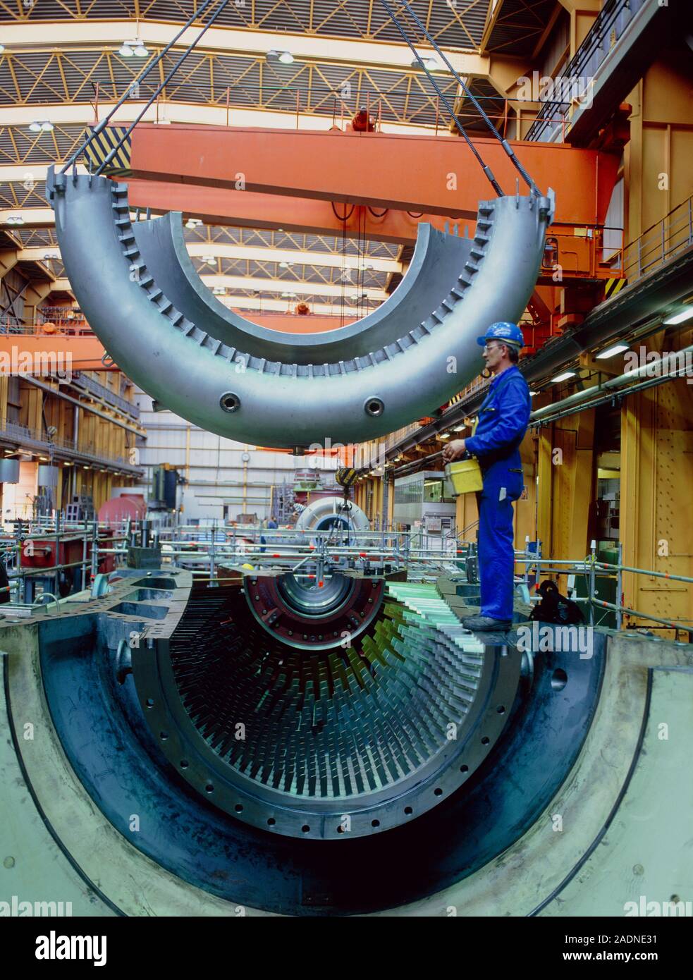 MODEL RELEASED. Gas turbine assembly. Worker controlling a crane during ...