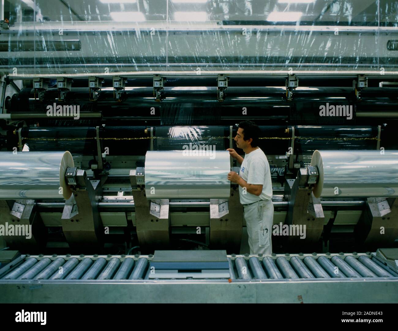Plastic film production. Worker monitoring the production of synthetic ...