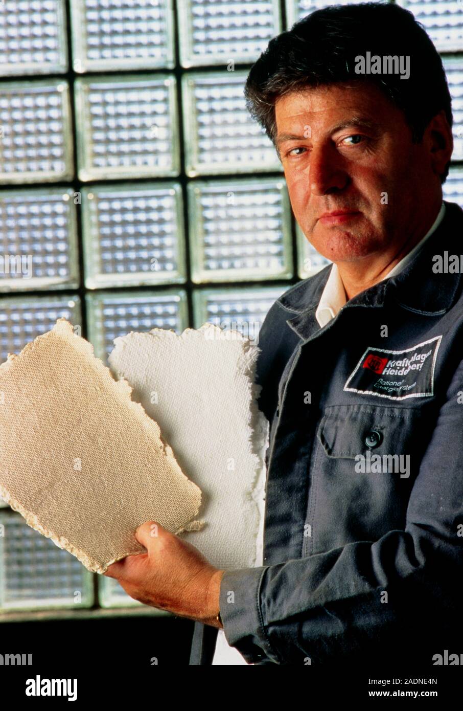 Paper manufacture. Technician showing two sheets of paper before (dark ...