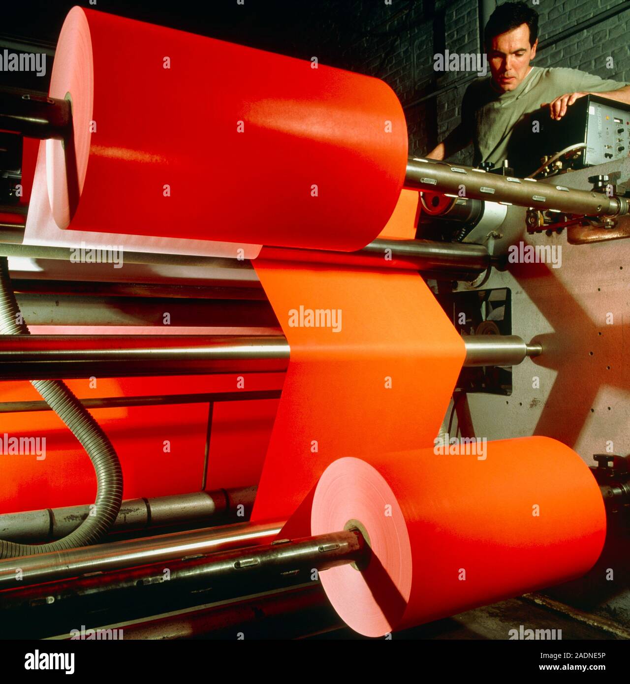 Paper coating. Technician monitoring part of the paper coating process ...