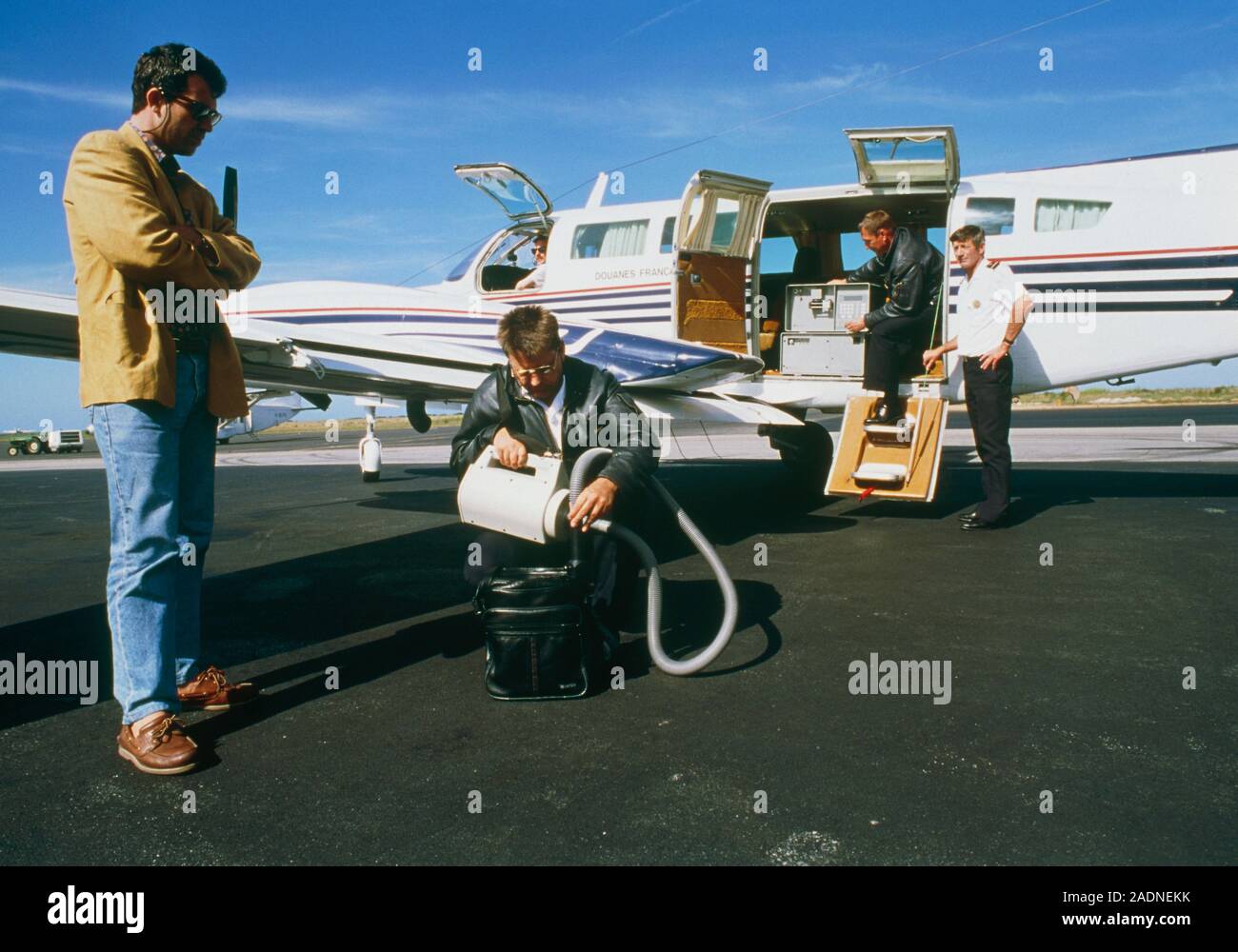 Customs check. Male customs officers checking a man's bag with the ...