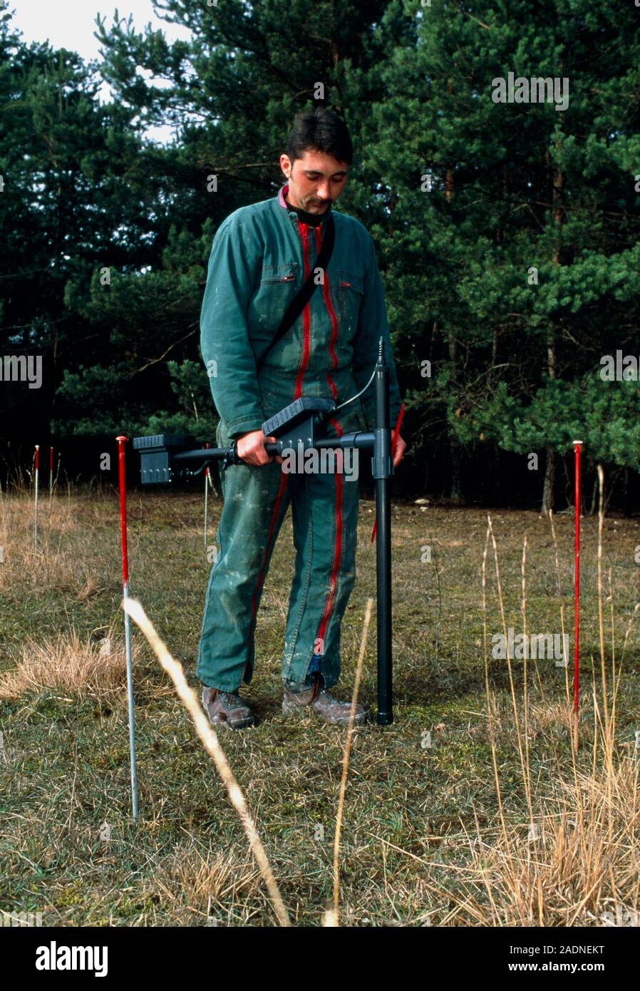 Mine clearing. Bomb disposal expert using a magnetometer to find mines ...
