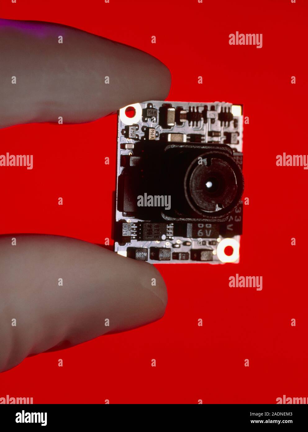 Miniature spy camera. Gloved fingers holding a miniature video camera ...