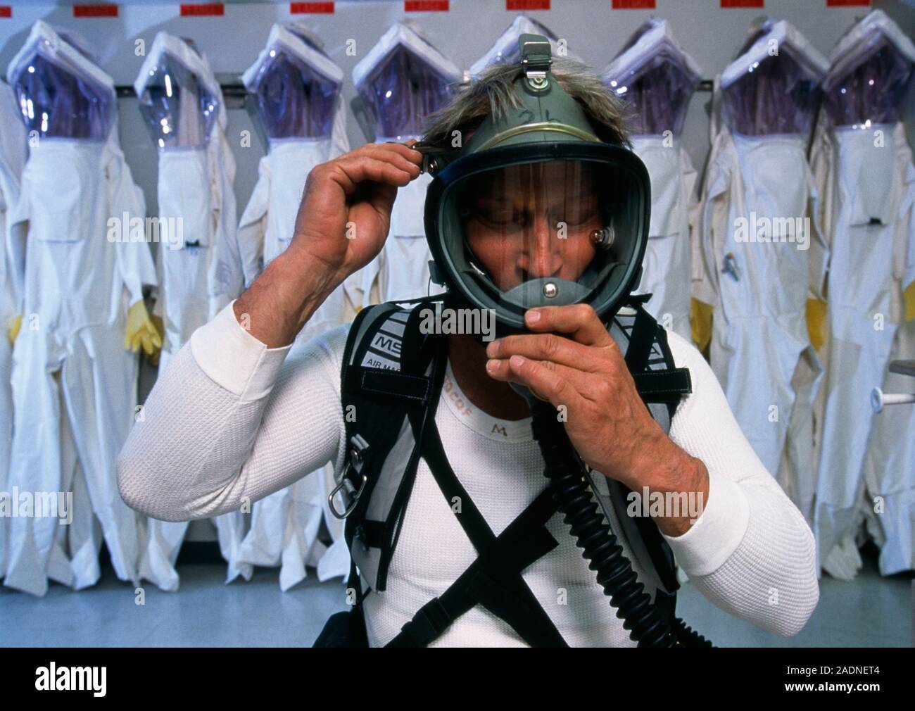 Chemical weapons disposal. Technician putting on a mask that makes up ...