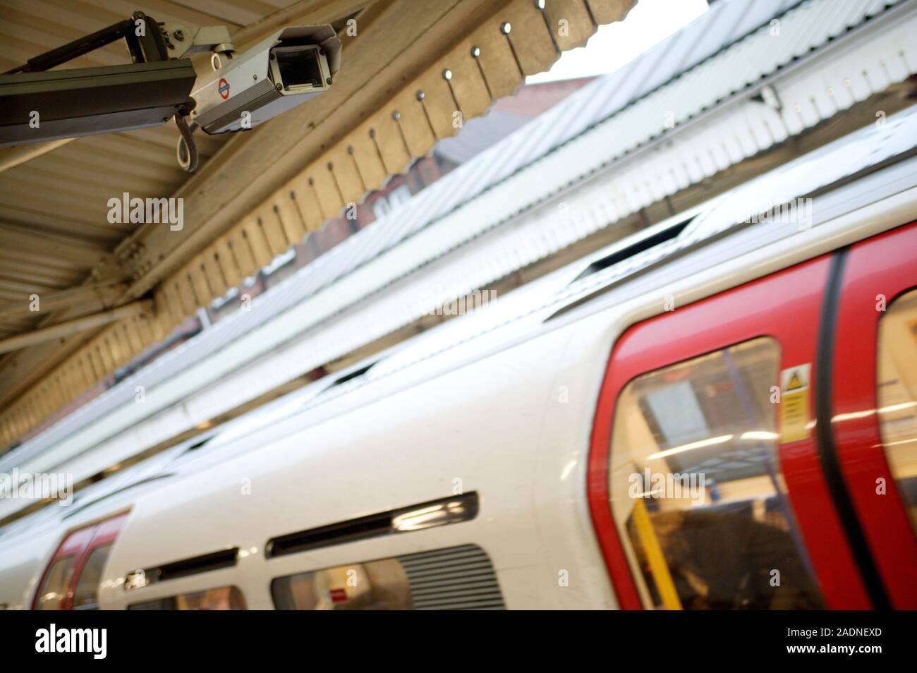 CCTV camera (upper left) in a London Underground station. A tube train ...