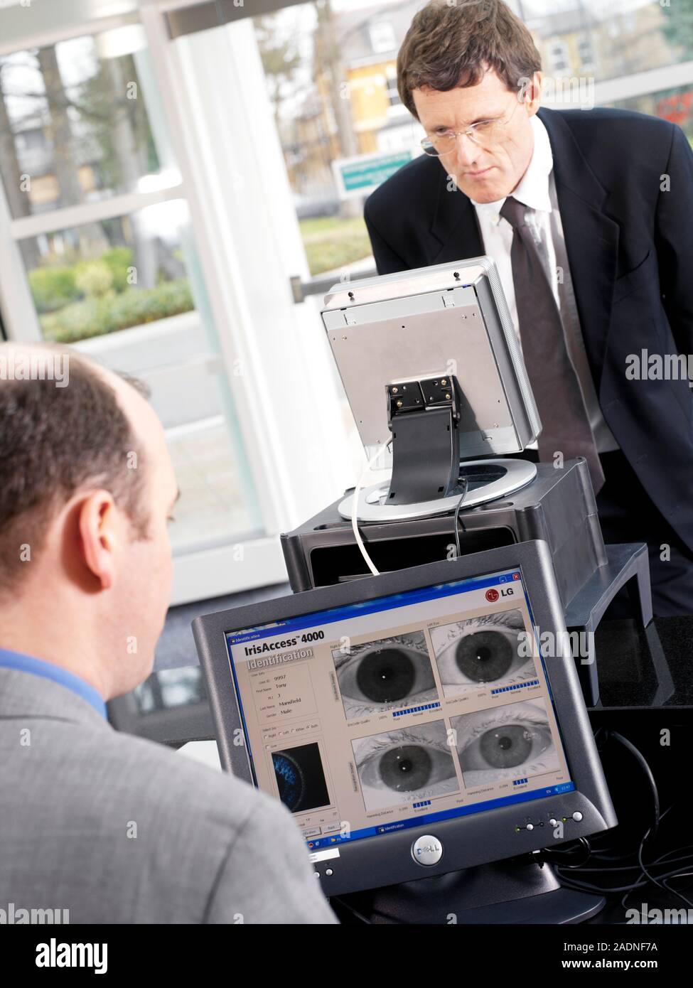Biometric eye scanning. Man (upper right) having his eyes screened by a ...