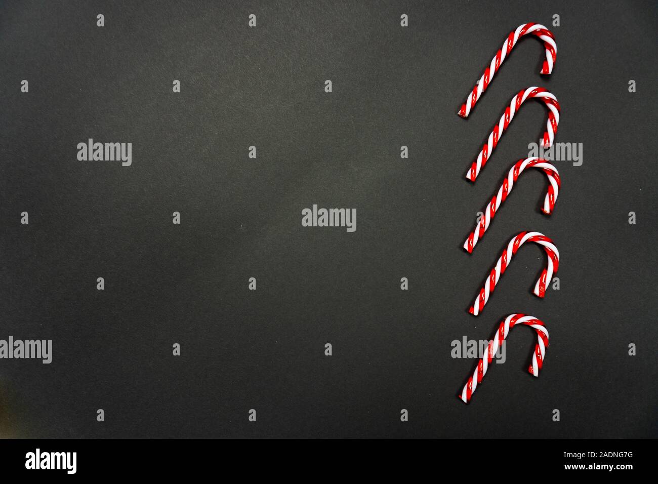 Five candy canes laying in a row on black background Stock Photo - Alamy