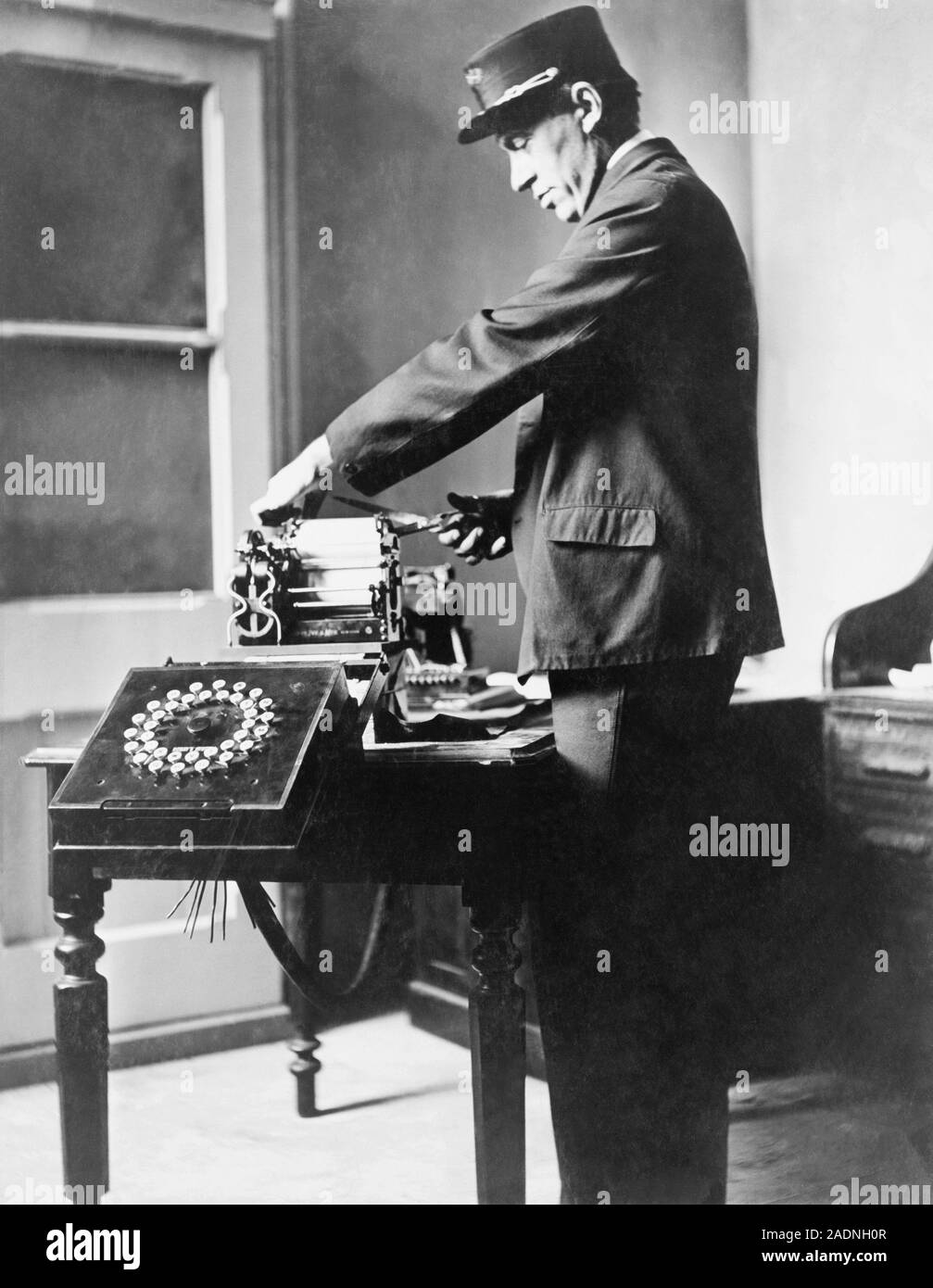 Telegraph operator using a pair of scissors to cut the print-out for a ...