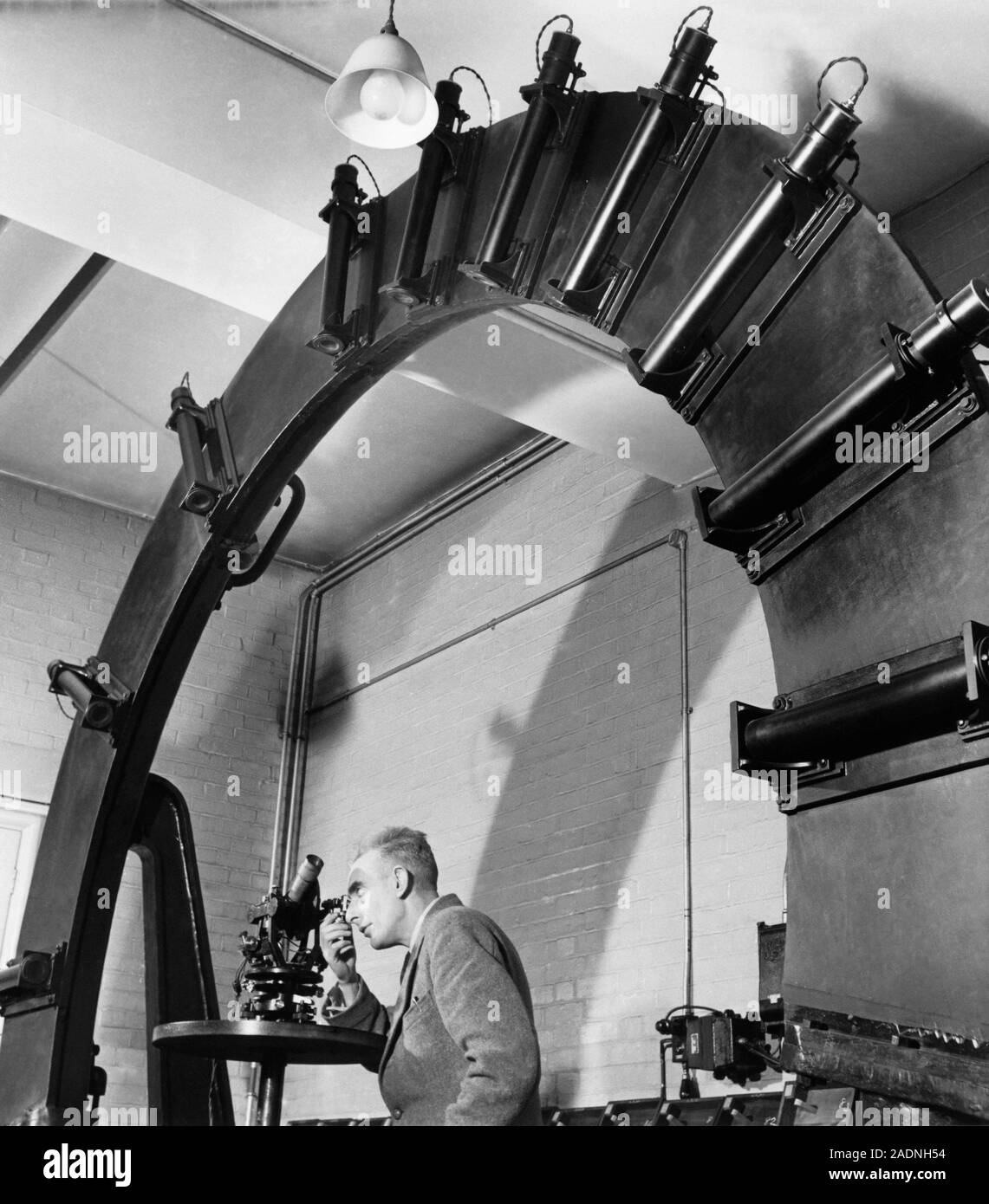 Vertical collimator. Researcher looking through the eyepiece of a ...