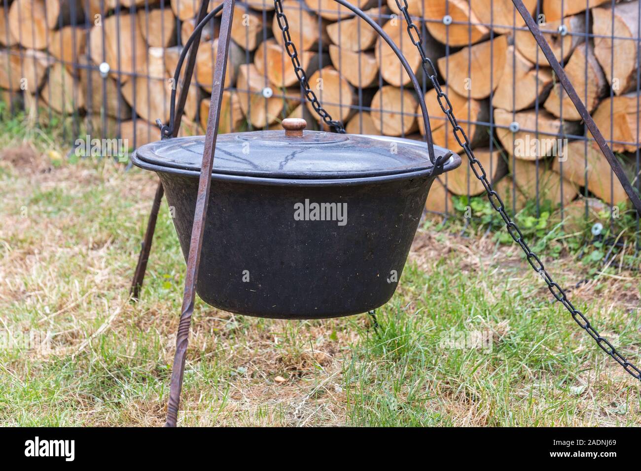 Metal cauldron hanging on metal sticks, stands on the green grass in ...