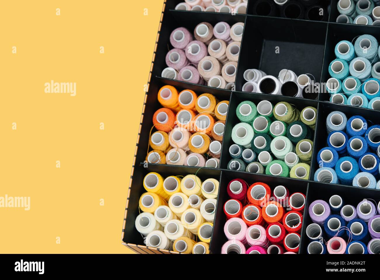 Set of color sewing threads in cardboard compartment box on yellow ...