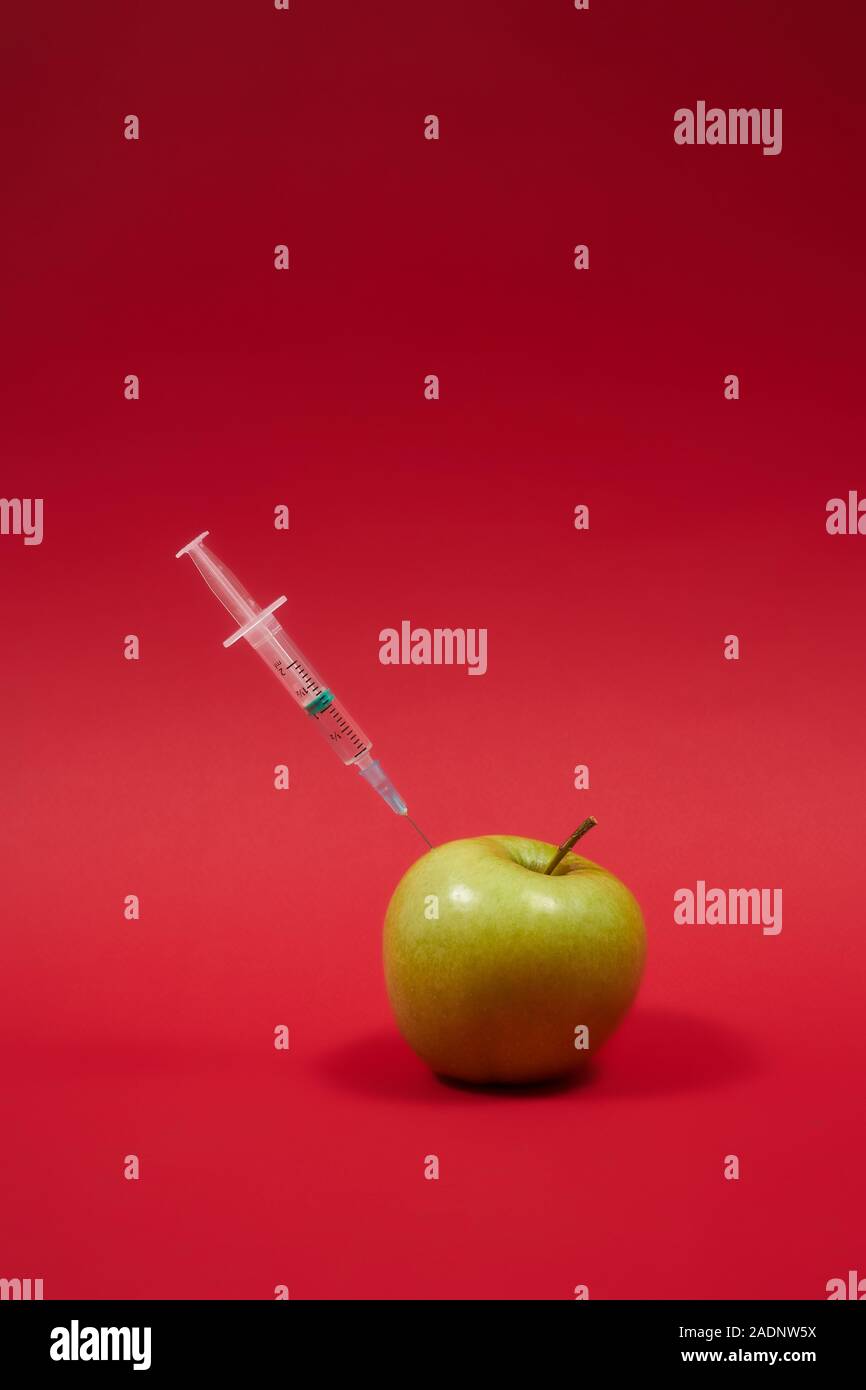 Poison enters the green apple. Syringe with liquid in fruit. GMO ...