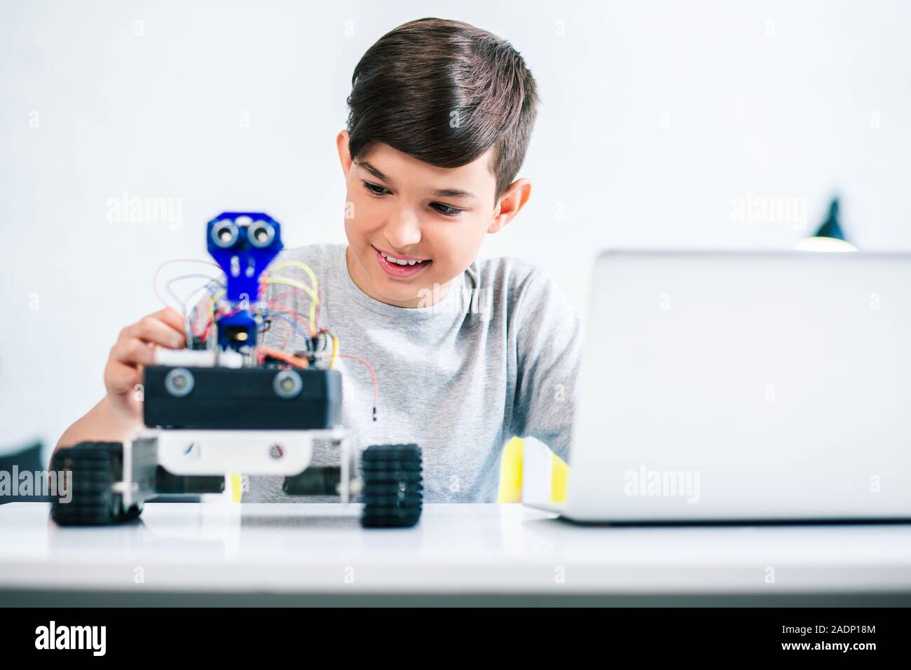 Waist up of a smiling boy testing modern robot Stock Photo - Alamy