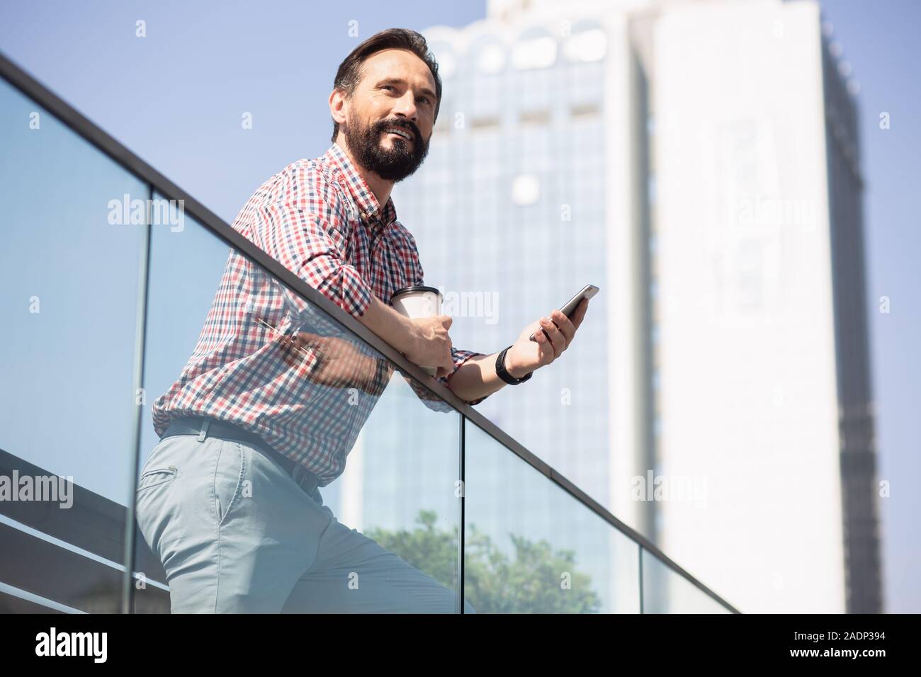 Low angle of a pleasant man using his smartphone Stock Photo - Alamy
