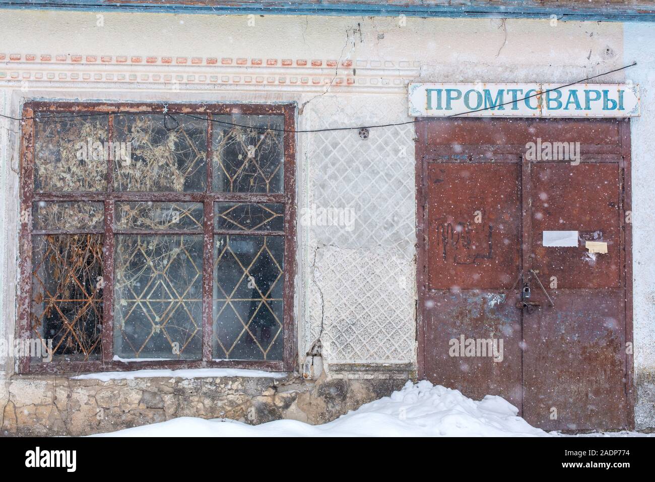 Abandoned old building with bars on the windows. Winter it's snowing ...