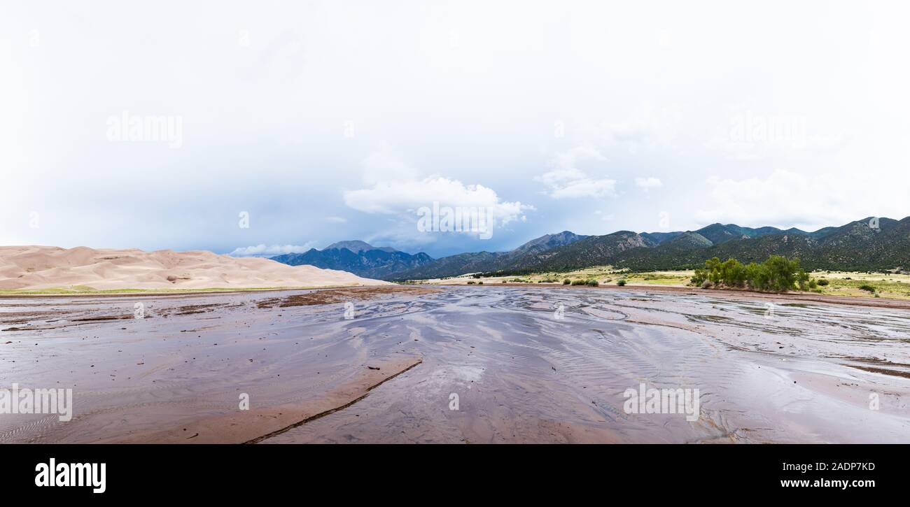 A muddy river separates the dunes and the rockies Stock Photo - Alamy
