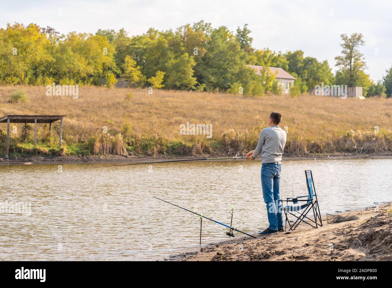 Man relaxing and fishing by lakeside Stock Photo - Alamy