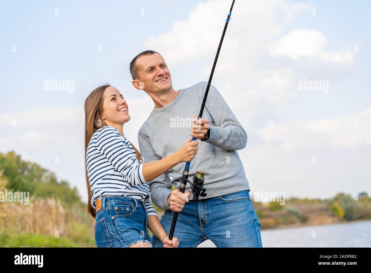Happy young couple fishing by lakeside Stock Photo - Alamy