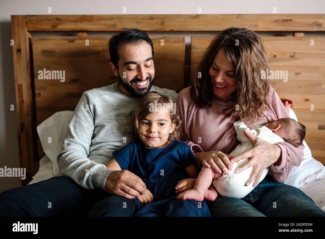 Smiling family snuggled together while mom breastfeeds newborn Stock ...
