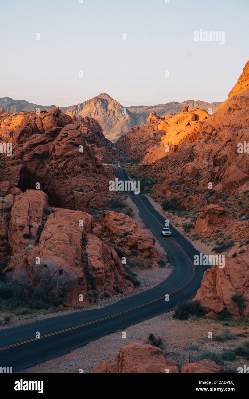 Car driving on a road trough a valley surrounded by red rocks Stock ...