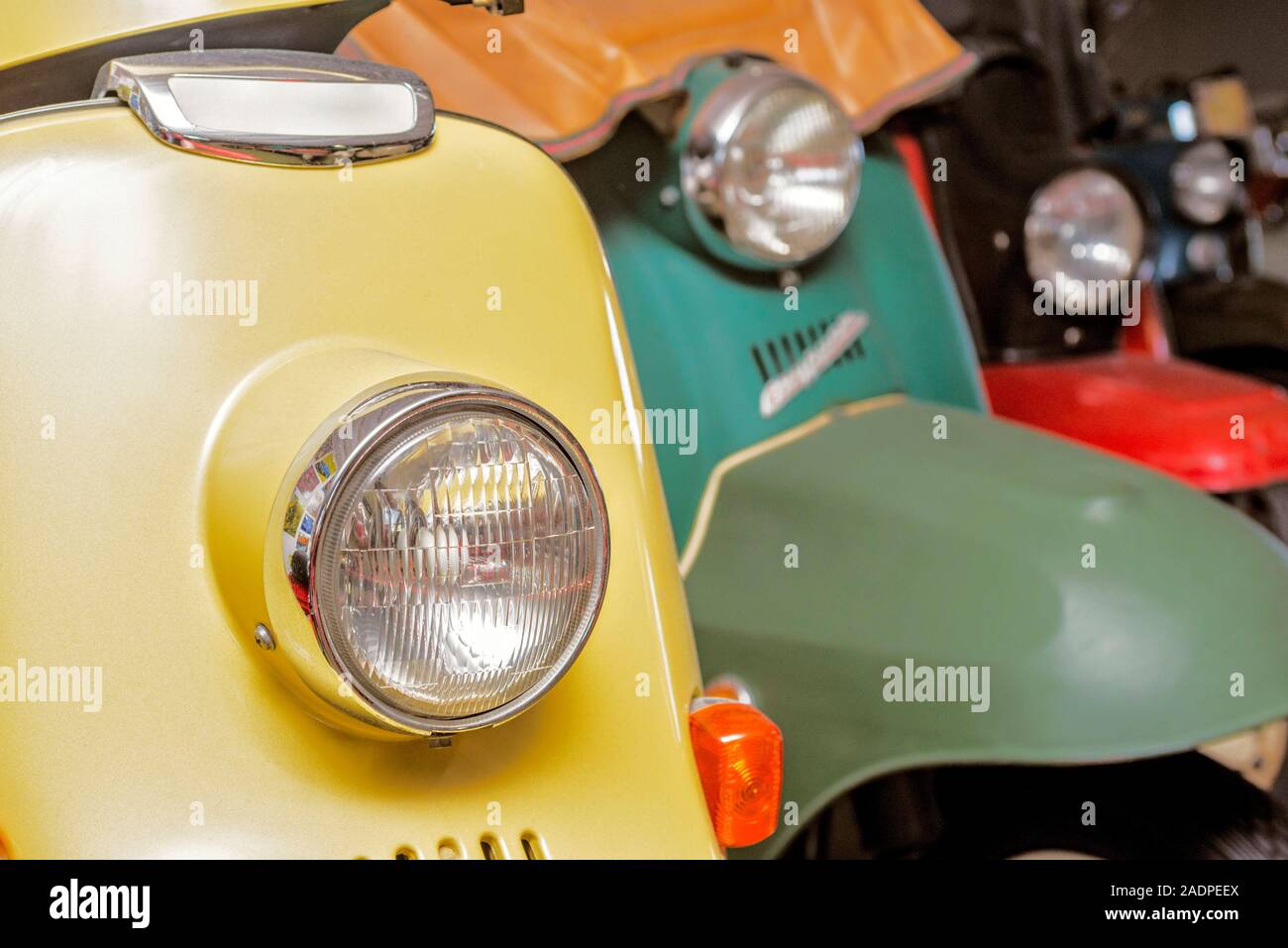 Parking mopeds of different colors. The spotlight of the moped close up ...