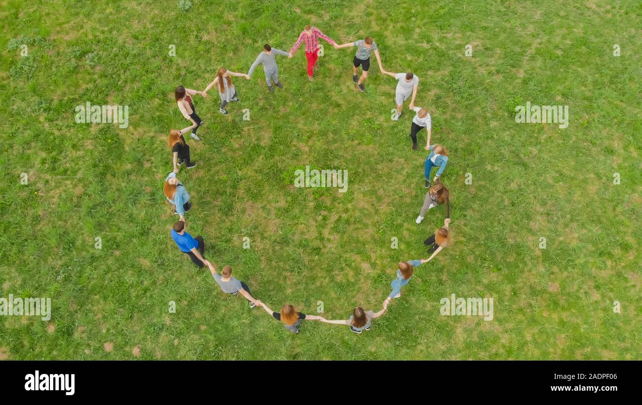 Friends in a circle holding hands make a round dance in the field Stock ...