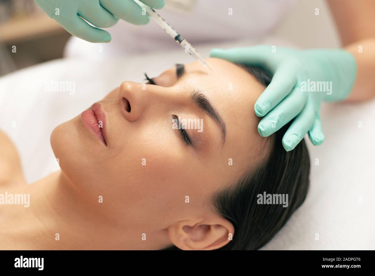 Face of calm woman and hand making injection into forehead Stock Photo ...