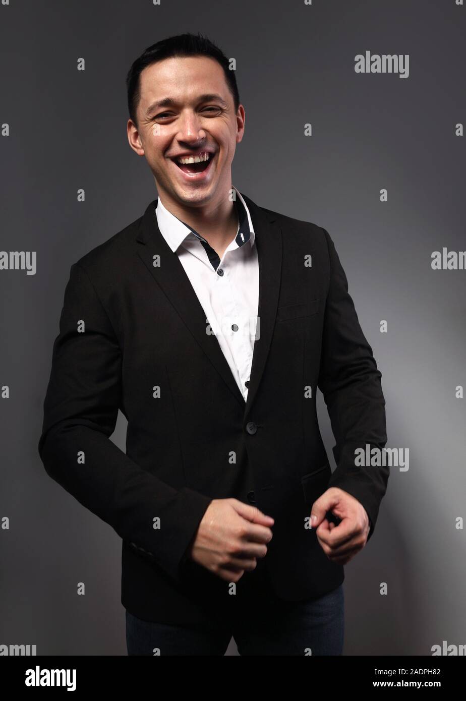 Happy fun young business man laughing in black suit clothing on grey ...