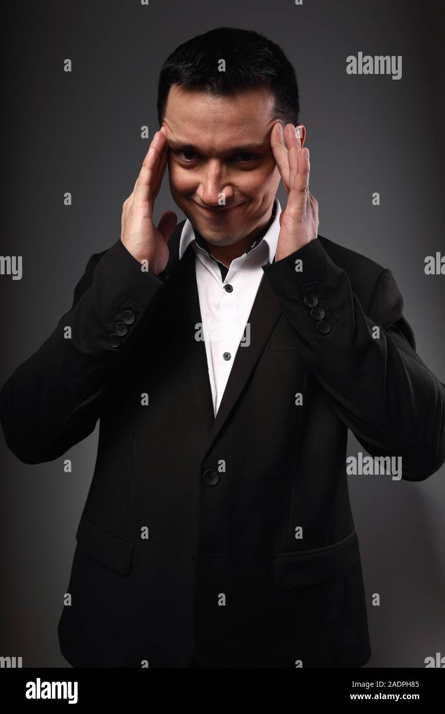 Serious thinking man looking in black suit on grey studio background ...