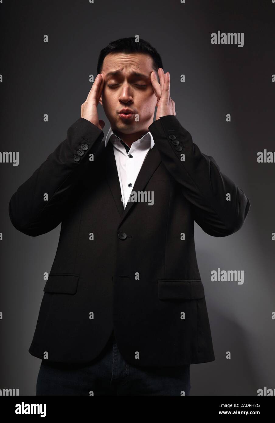 Serious thinking man looking in black suit on grey studio background ...