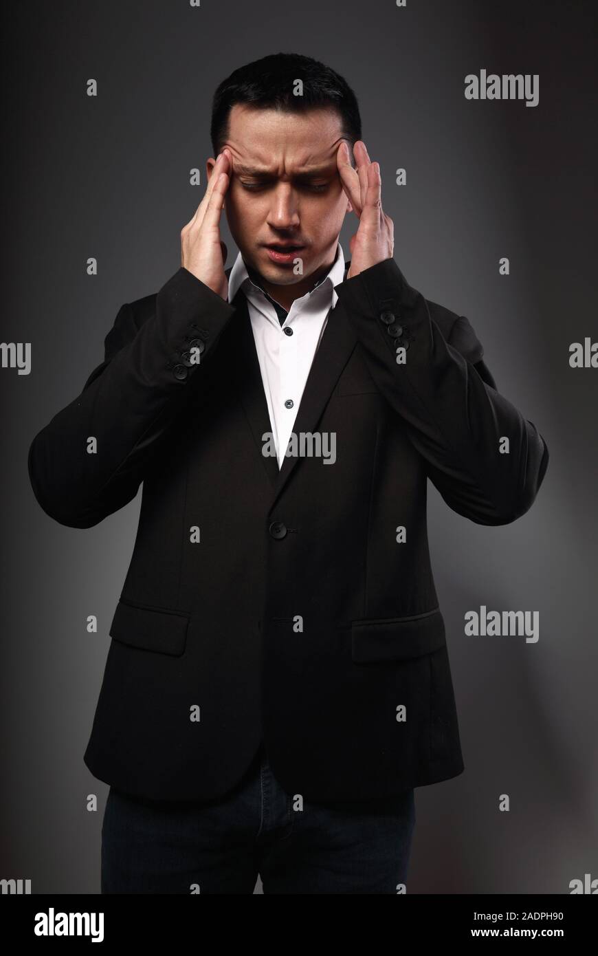 Serious thinking man looking in black suit on grey studio background ...