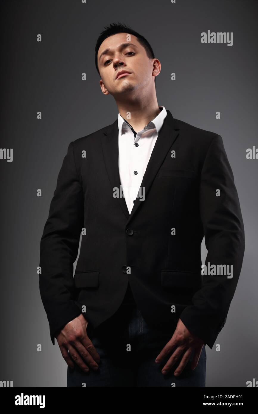 Serious thinking man looking in black suit on grey studio background ...