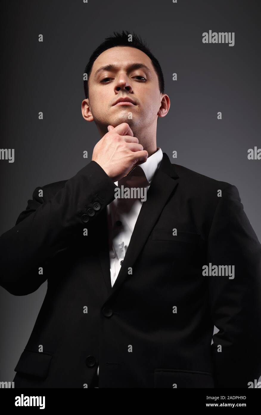 Serious thinking man looking in black suit on grey studio background ...