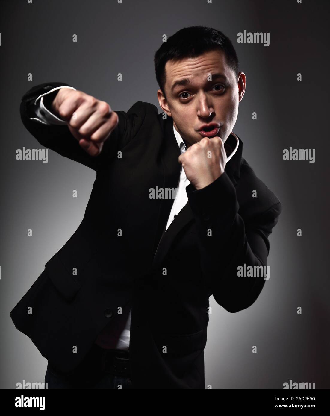 Angry business man fighting and making the hit by the fist on grey ...