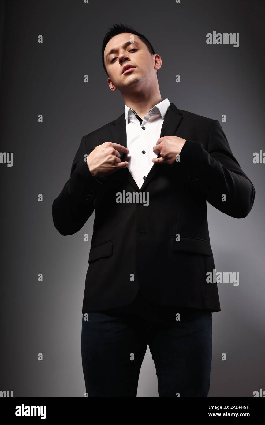 Serious thinking man looking in black fashion suit on grey studio ...