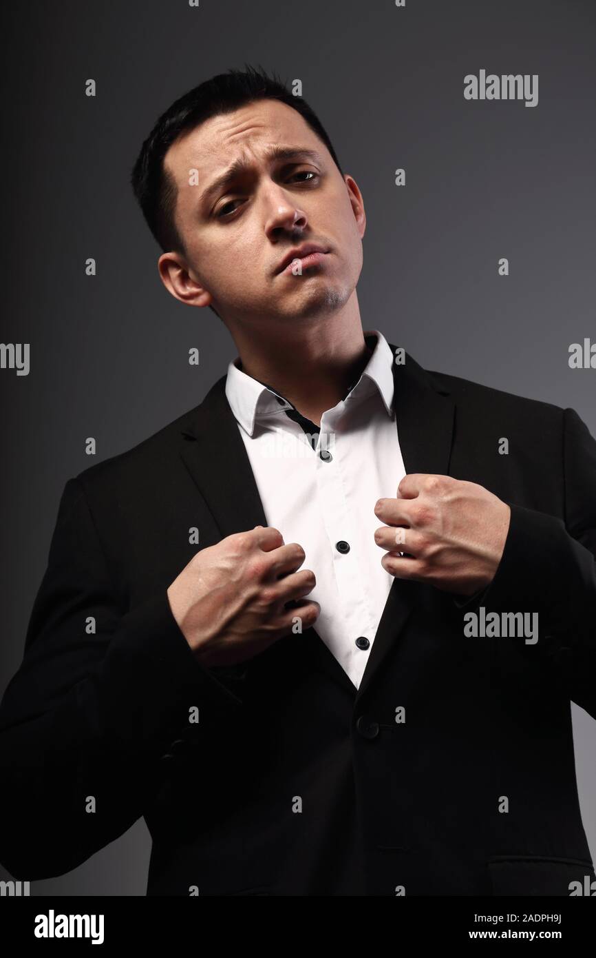 Serious thinking man looking in black suit on grey studio background ...