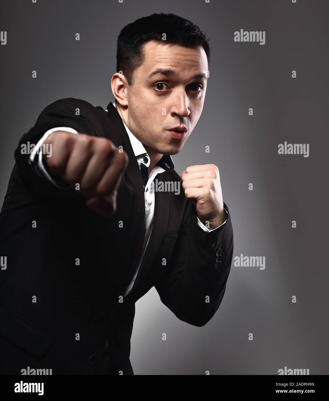 Angry business man fighting and making the hit by the fist on grey ...