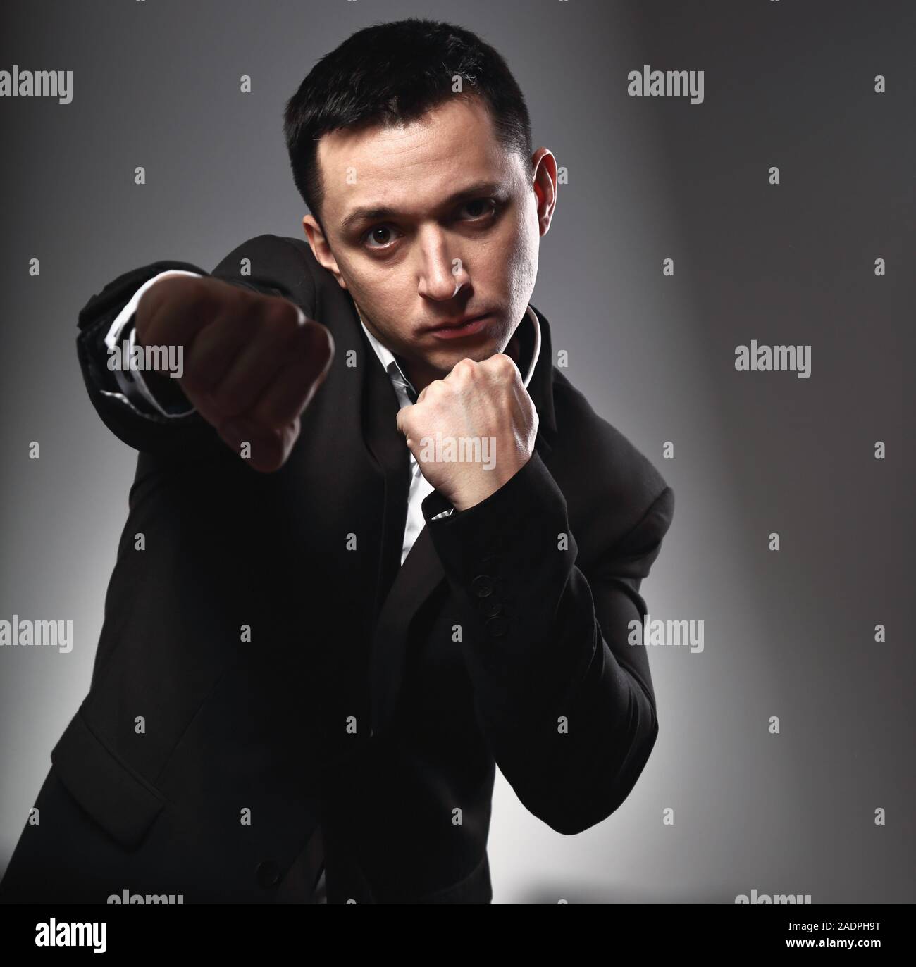 Angry business man fighting and making the hit by the fist on grey ...