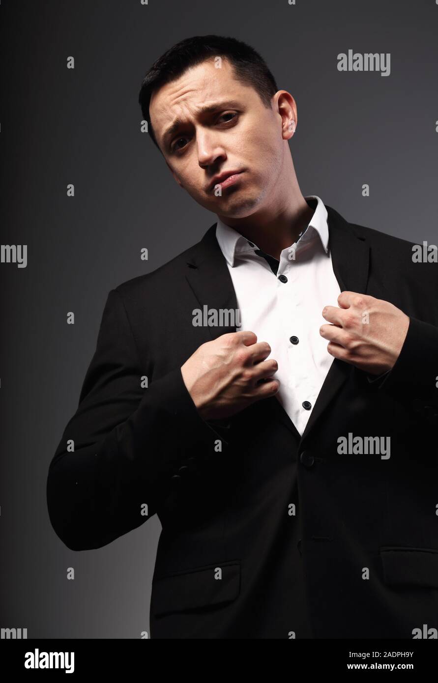 Serious thinking man looking in black suit on grey studio background ...