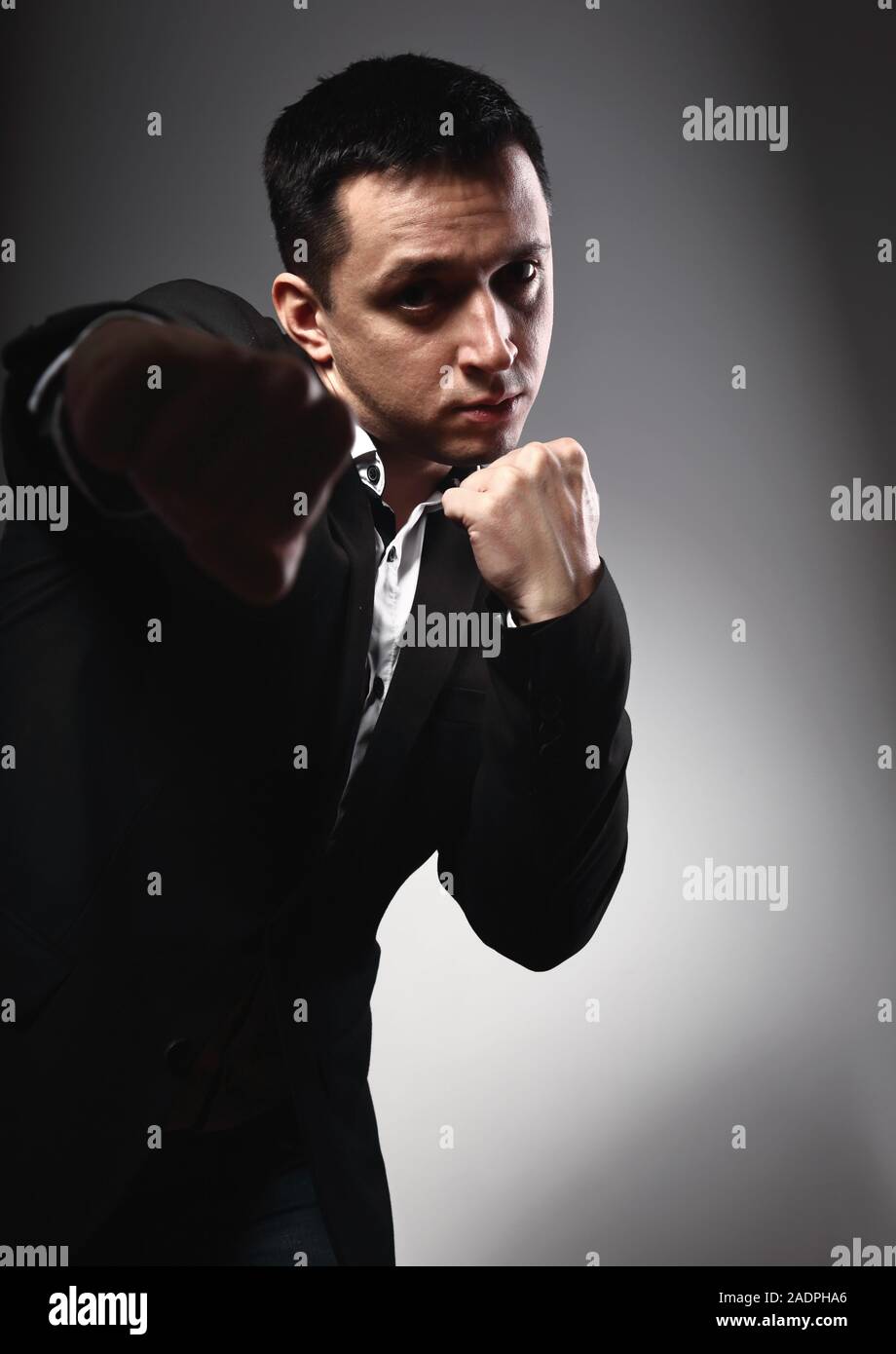 Angry business man fighting and making the hit by the fist on grey ...