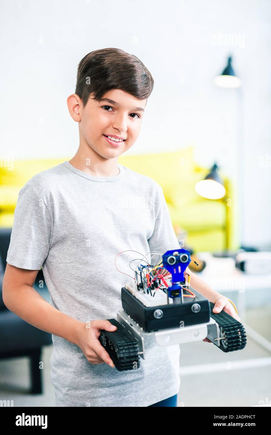 Waist up of a nice smiling boy holding his robot Stock Photo - Alamy